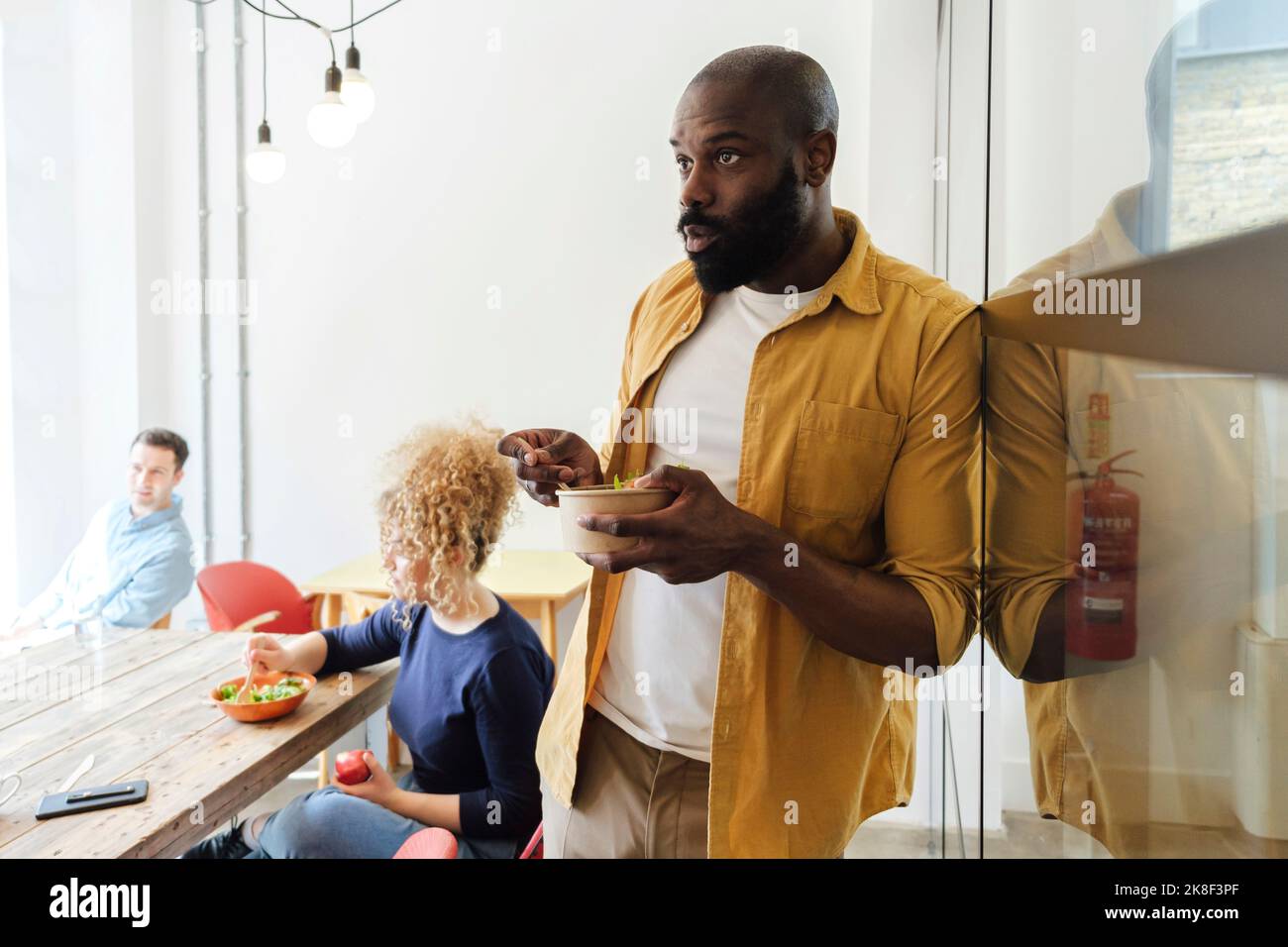 Smiling businessman eating lunch in staff room leaning on wall Stock ...