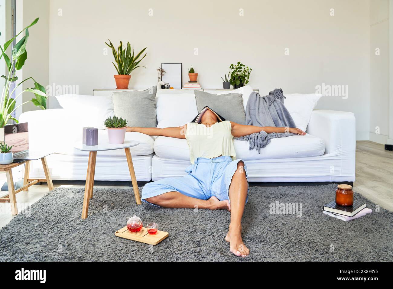 Woman with diary on face leaning with arms outstretched in living room ...