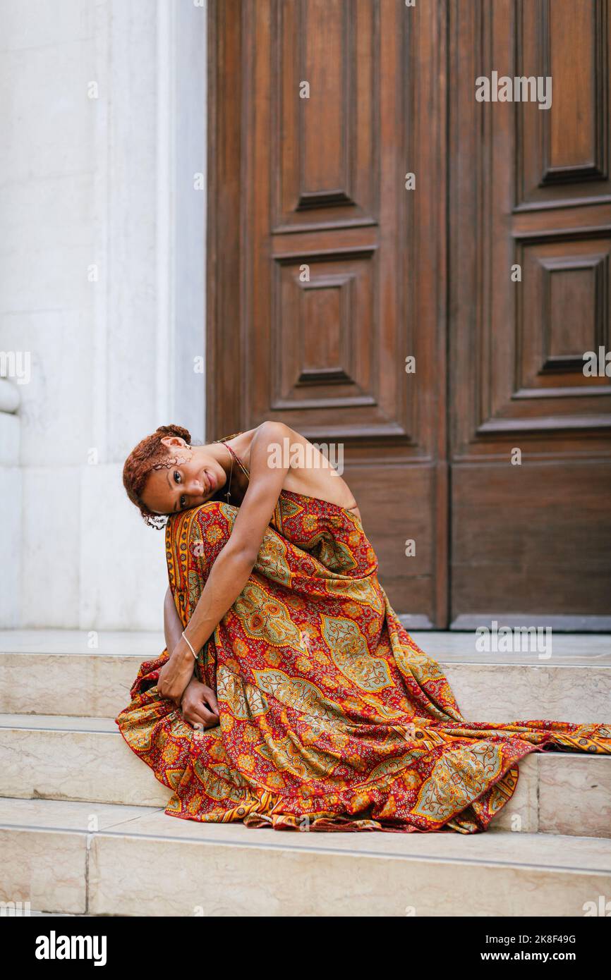 Young woman hugging knees sitting in front of door on steps Stock Photo ...