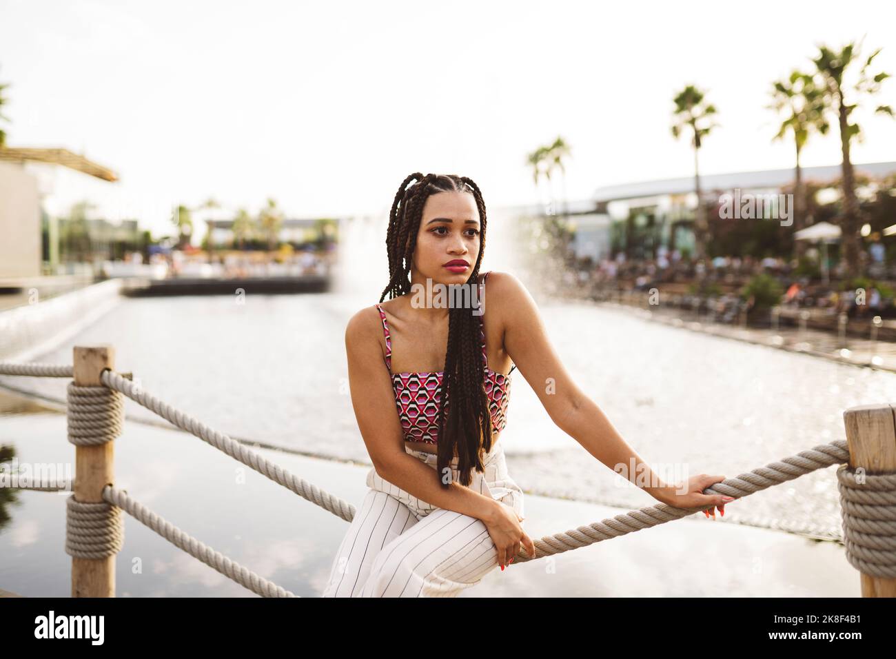 Thoughtful young woman sitting on rope fence Stock Photo - Alamy