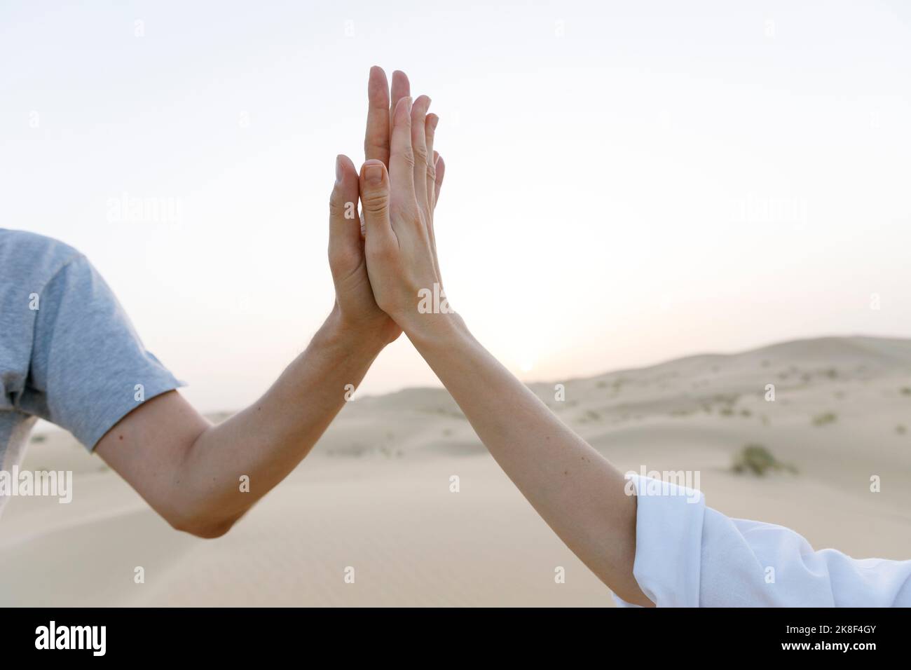 Hands of couple giving high-five in desert at sunset Stock Photo - Alamy