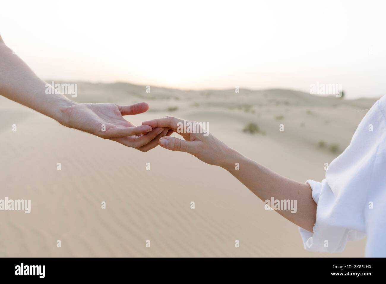 Couple holding hands in desert at sunset Stock Photo - Alamy
