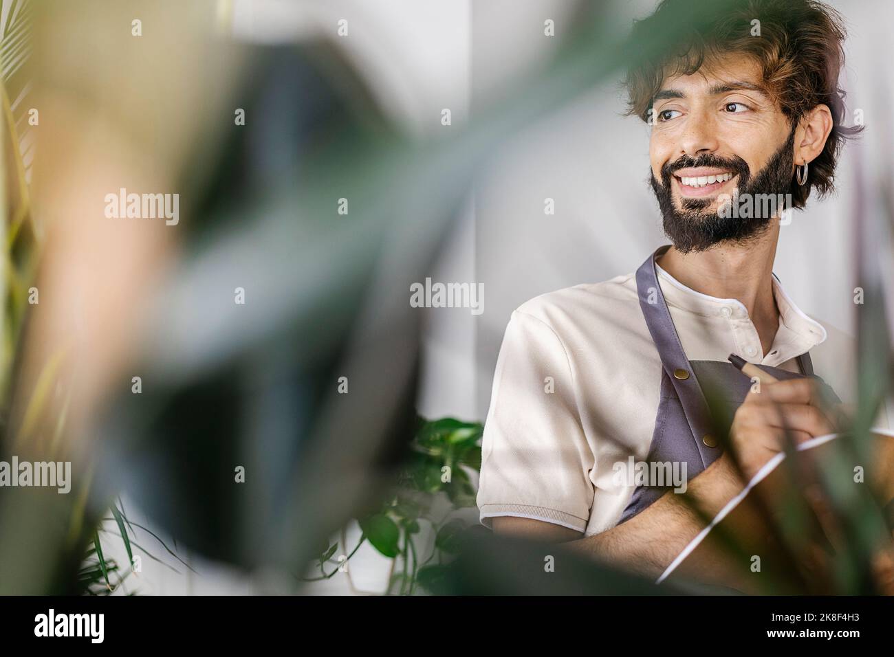 Happy owner of plant shop holding pen and book Stock Photo - Alamy