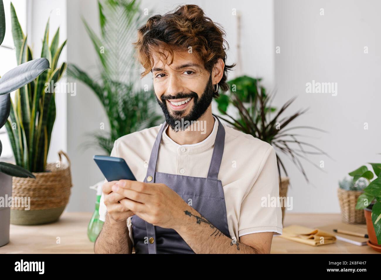 Happy owner of plant shop holding mobile phone Stock Photo - Alamy