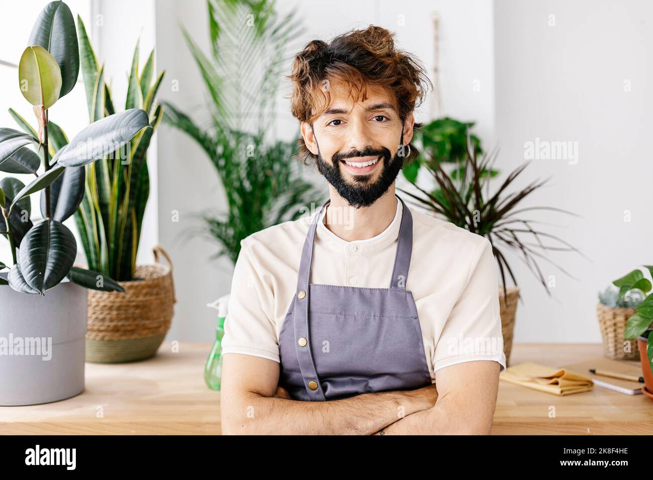 Smiling owner of plant shop standing with arms crossed Stock Photo - Alamy
