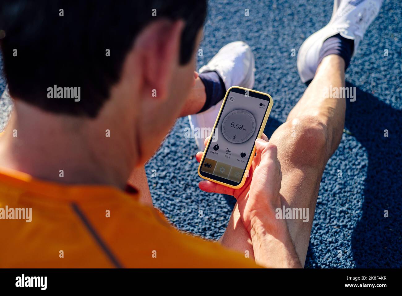 Sportsman holding mobile phone sitting on track Stock Photo - Alamy