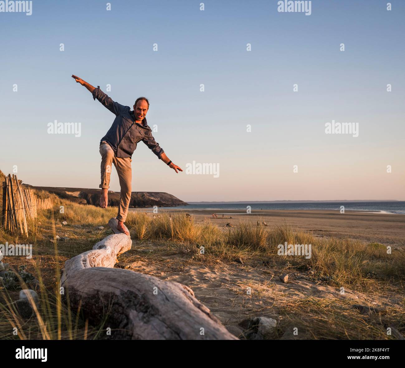 Playful man with arms outstretched balancing on log Stock Photo - Alamy