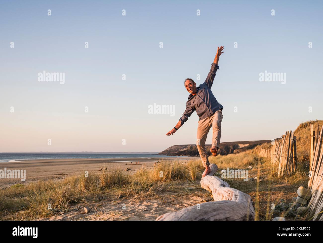 Cheerful mature man having fun on log at beach Stock Photo - Alamy