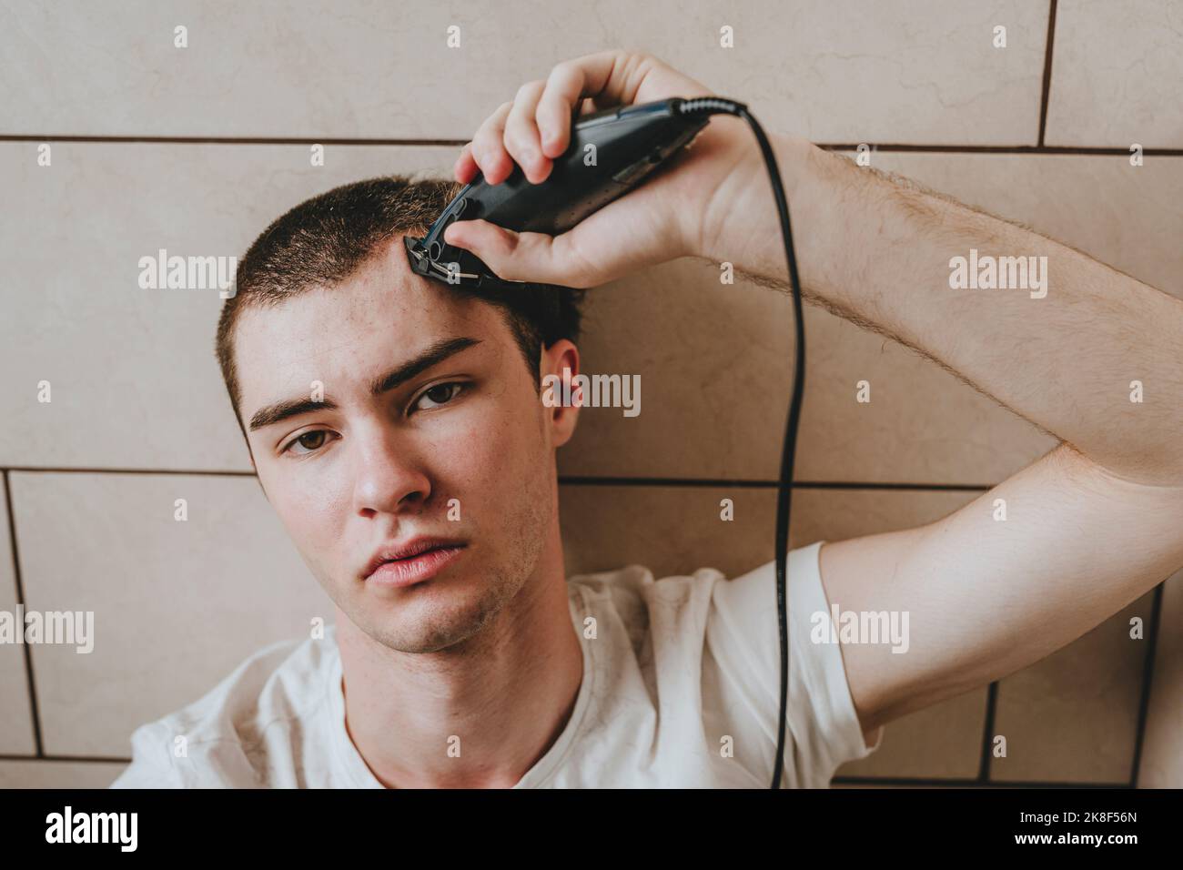 Lonely young man shaving hair with electric razor in bathroom Stock ...
