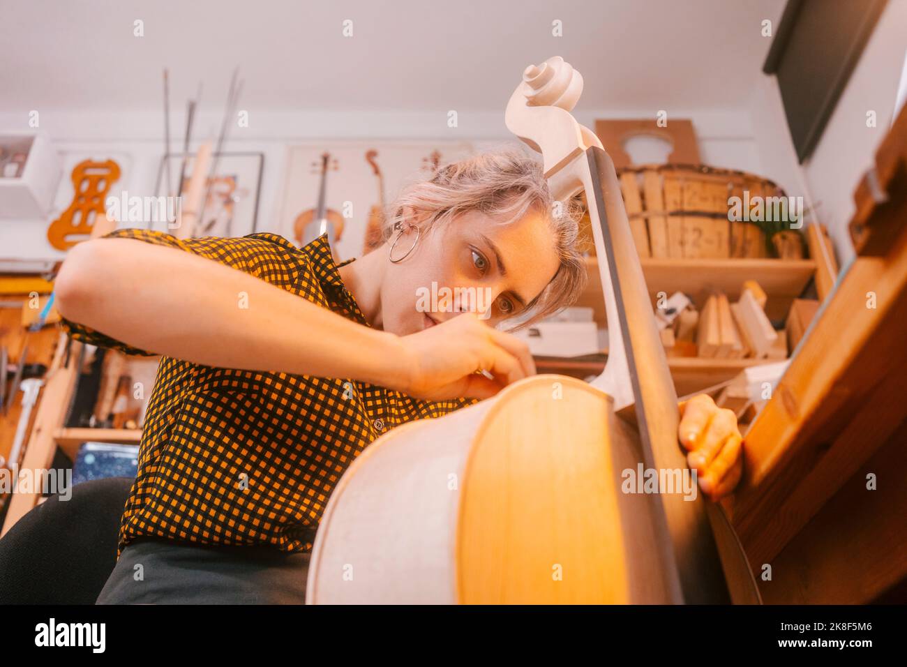 Luthier working on double bass in musical instrument workshop Stock ...