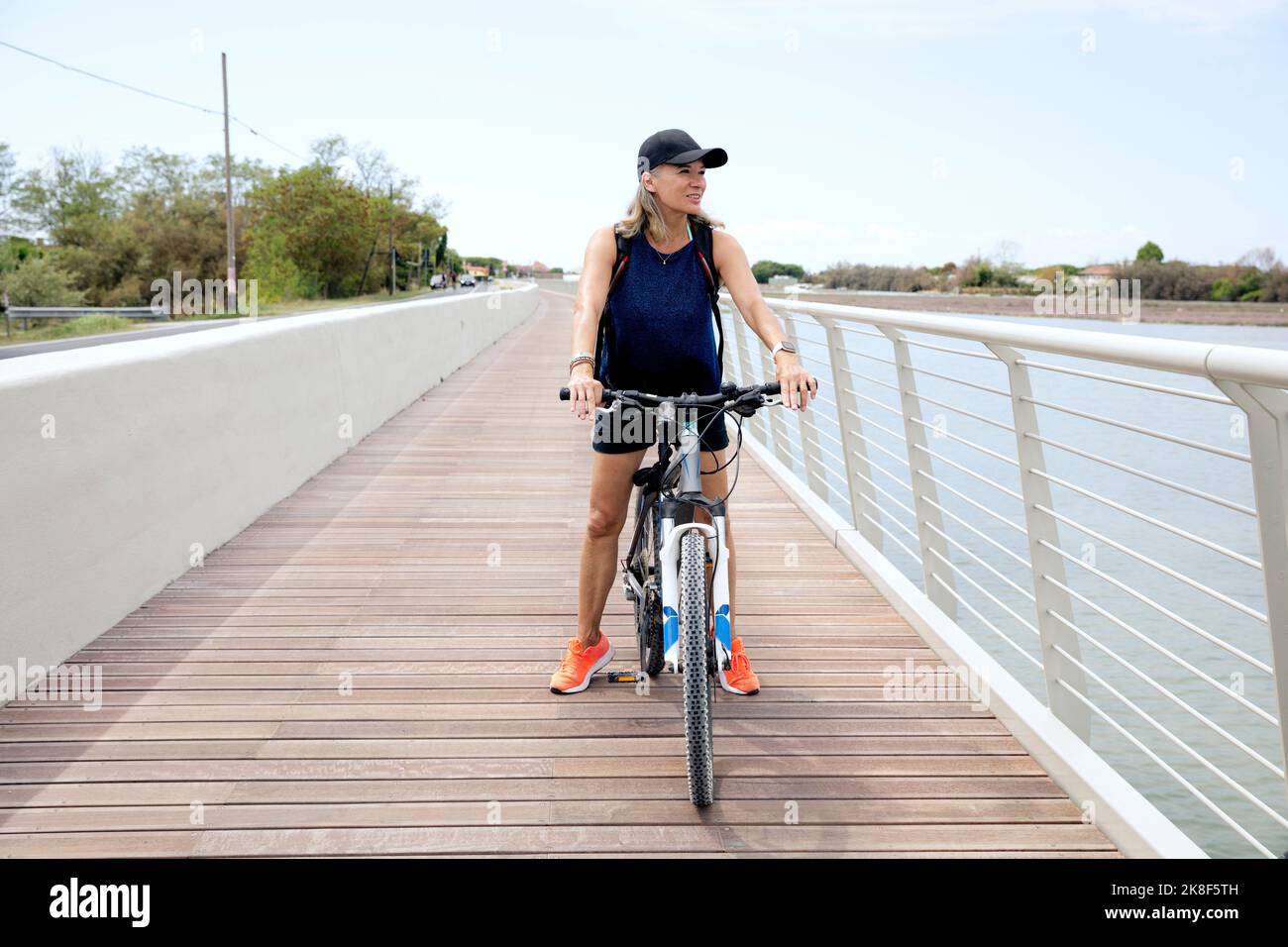 Active senior woman riding bicycle on promenade Stock Photo - Alamy