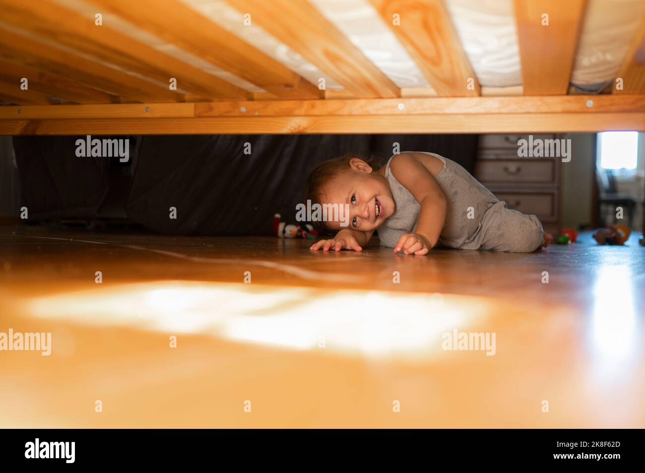 Happy boy looking under bed at home Stock Photo - Alamy
