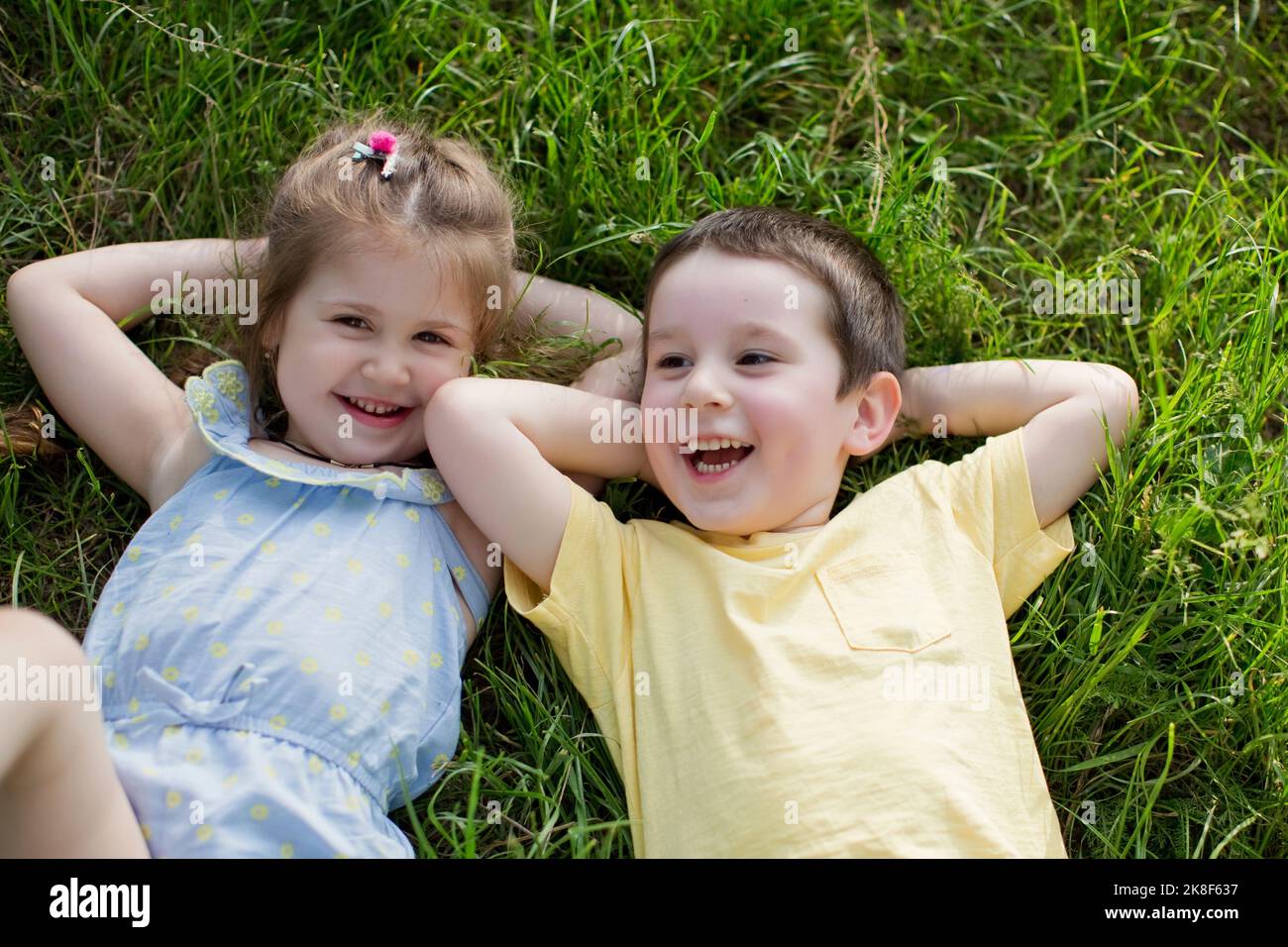 Smiling siblings relaxing on grass hi-res stock photography and images ...