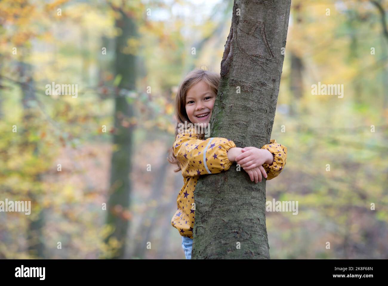 Happy cute girl hugging tree in forest Stock Photo - Alamy