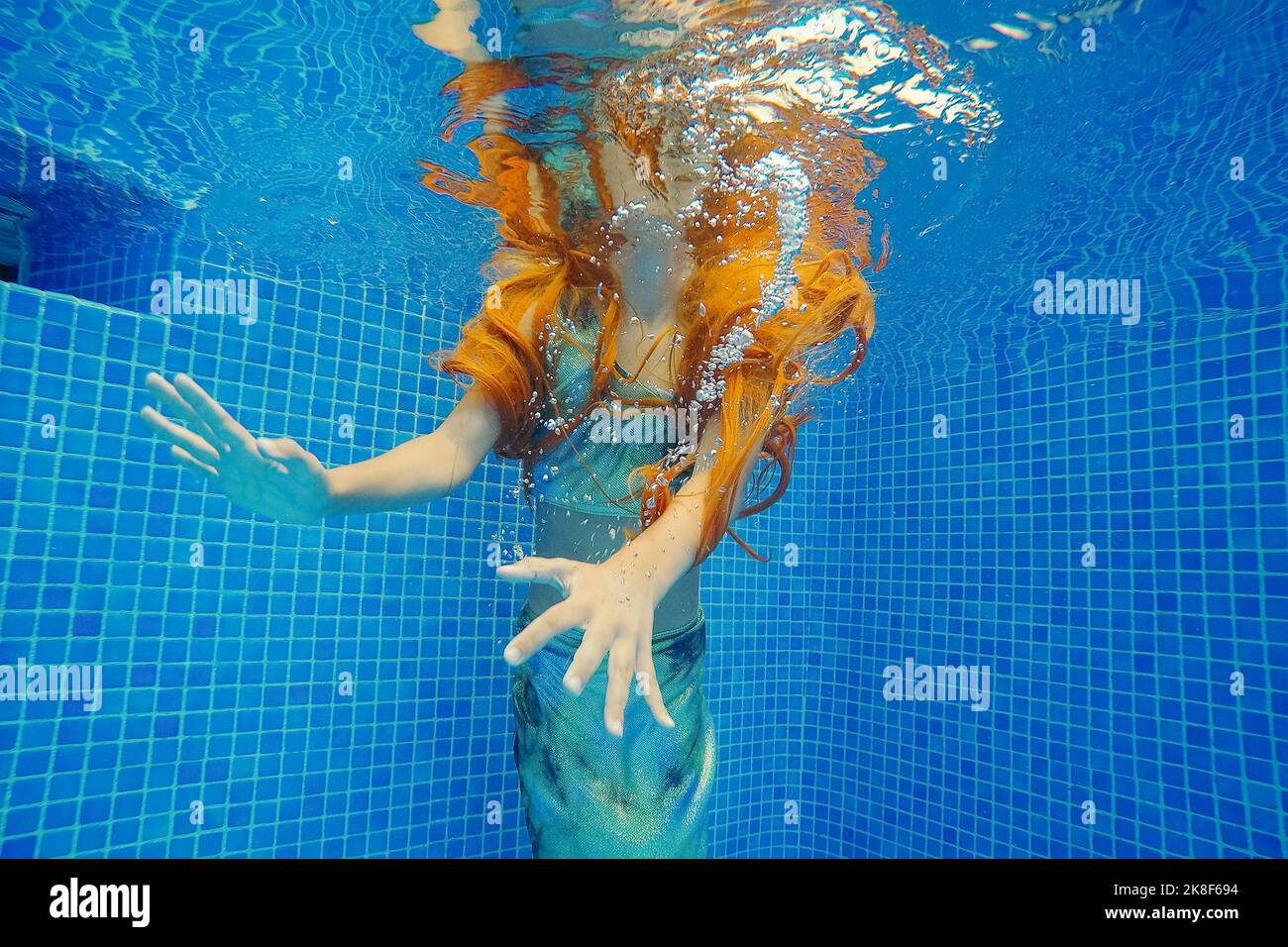 Redhead girl swimming underwater in pool Stock Photo - Alamy