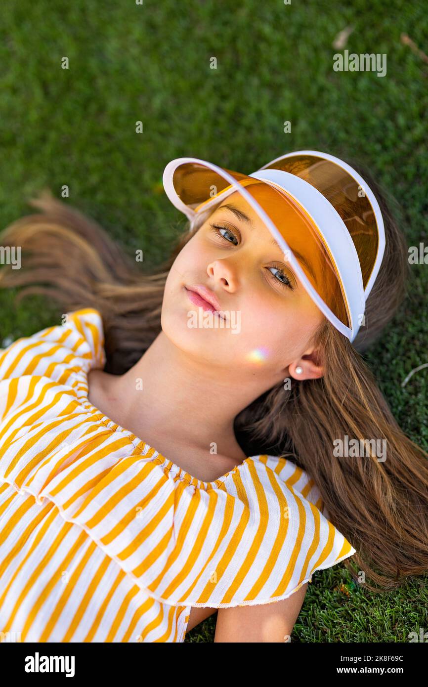 Girl wearing sun visor lying on grass Stock Photo - Alamy