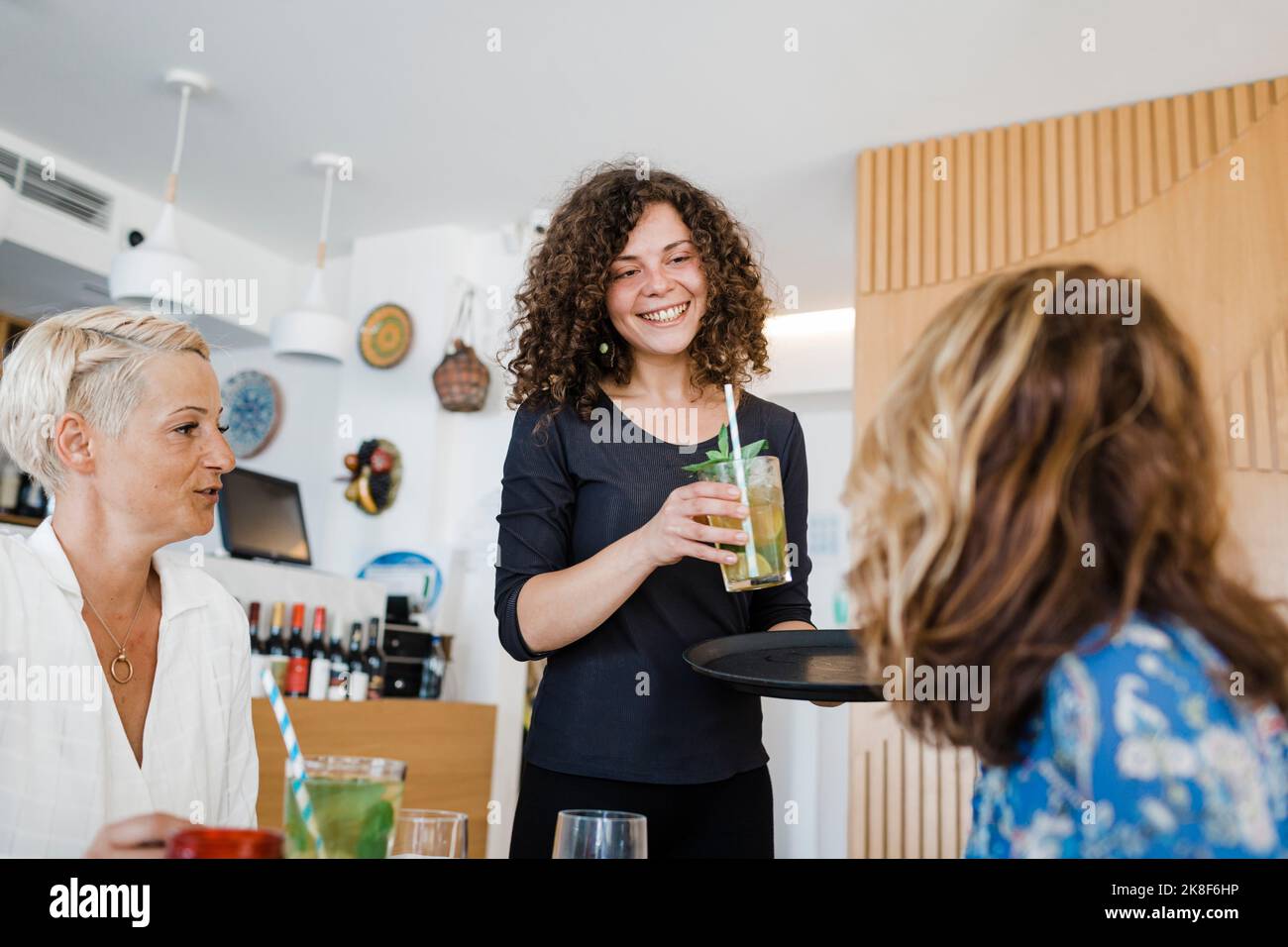 Happy young waitress serving cocktails to customers at restaurant Stock ...