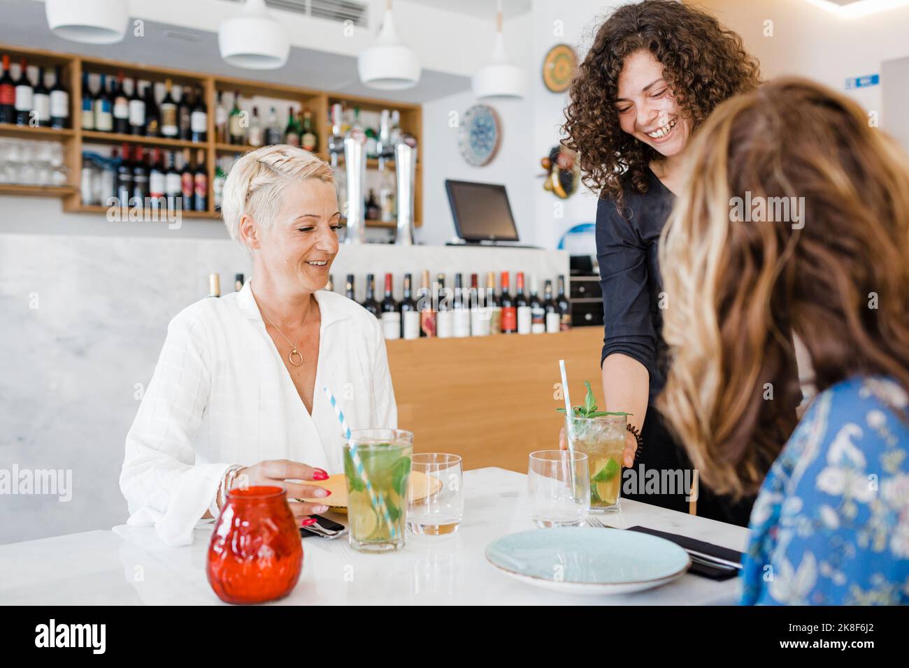 Happy waitress serving cocktails to customers in restaurant Stock Photo ... Happy waitress serving cocktails to customers in restaurant Stock Photo ...