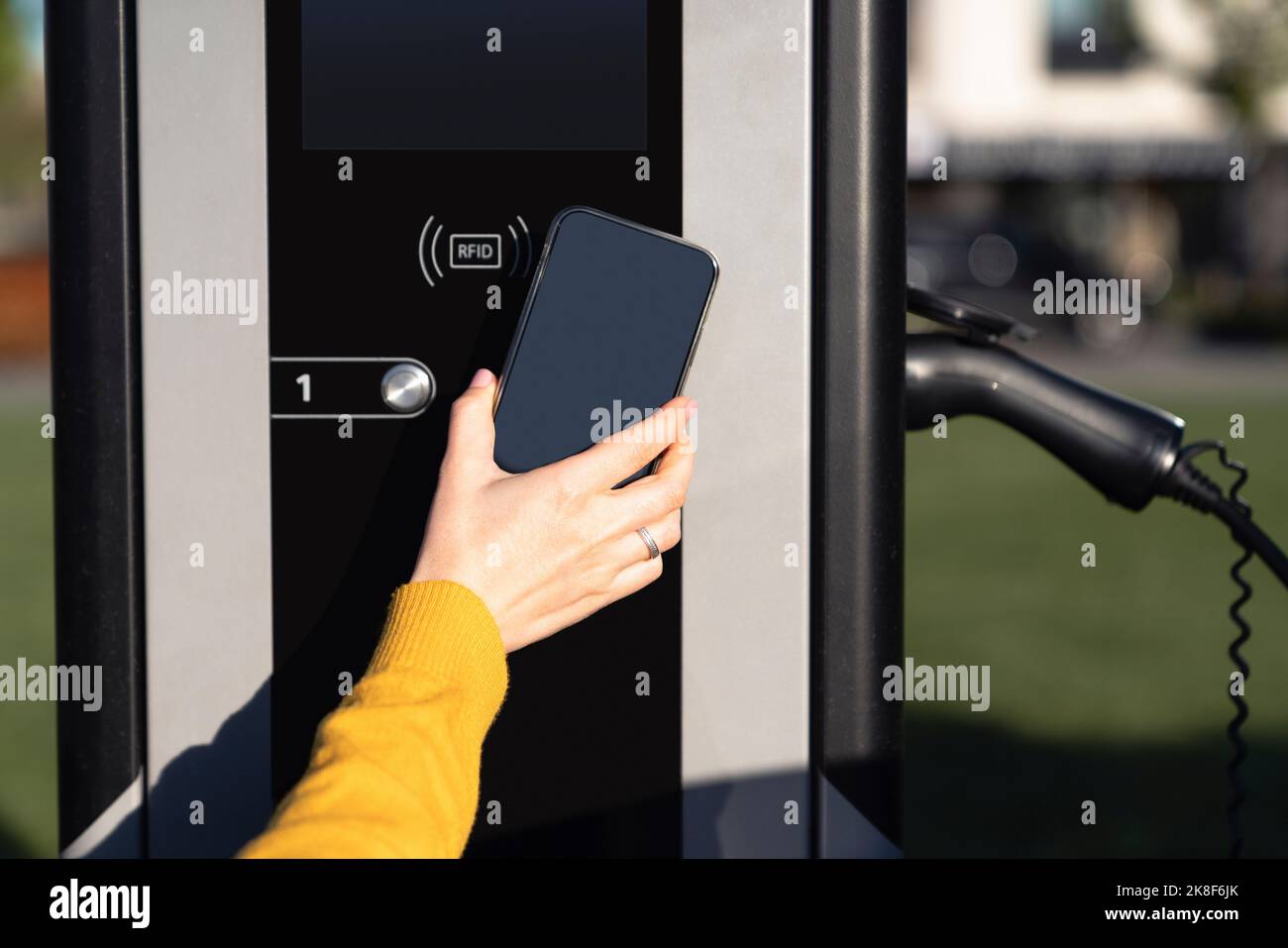 Hand of woman making payment through smart phone at vehicle charging ...