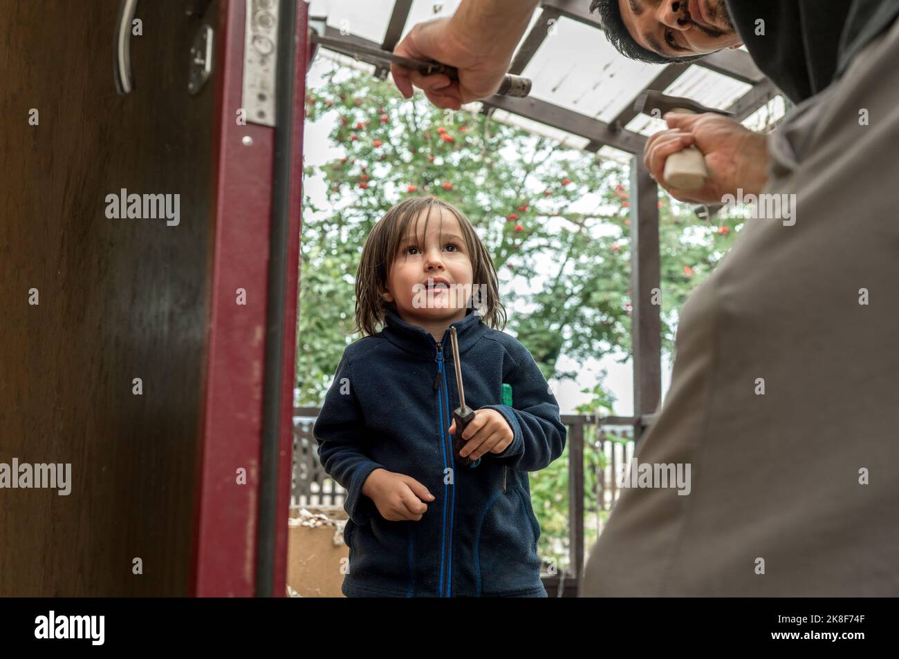 Boy looking at father repairing door lock Stock Photo - Alamy
