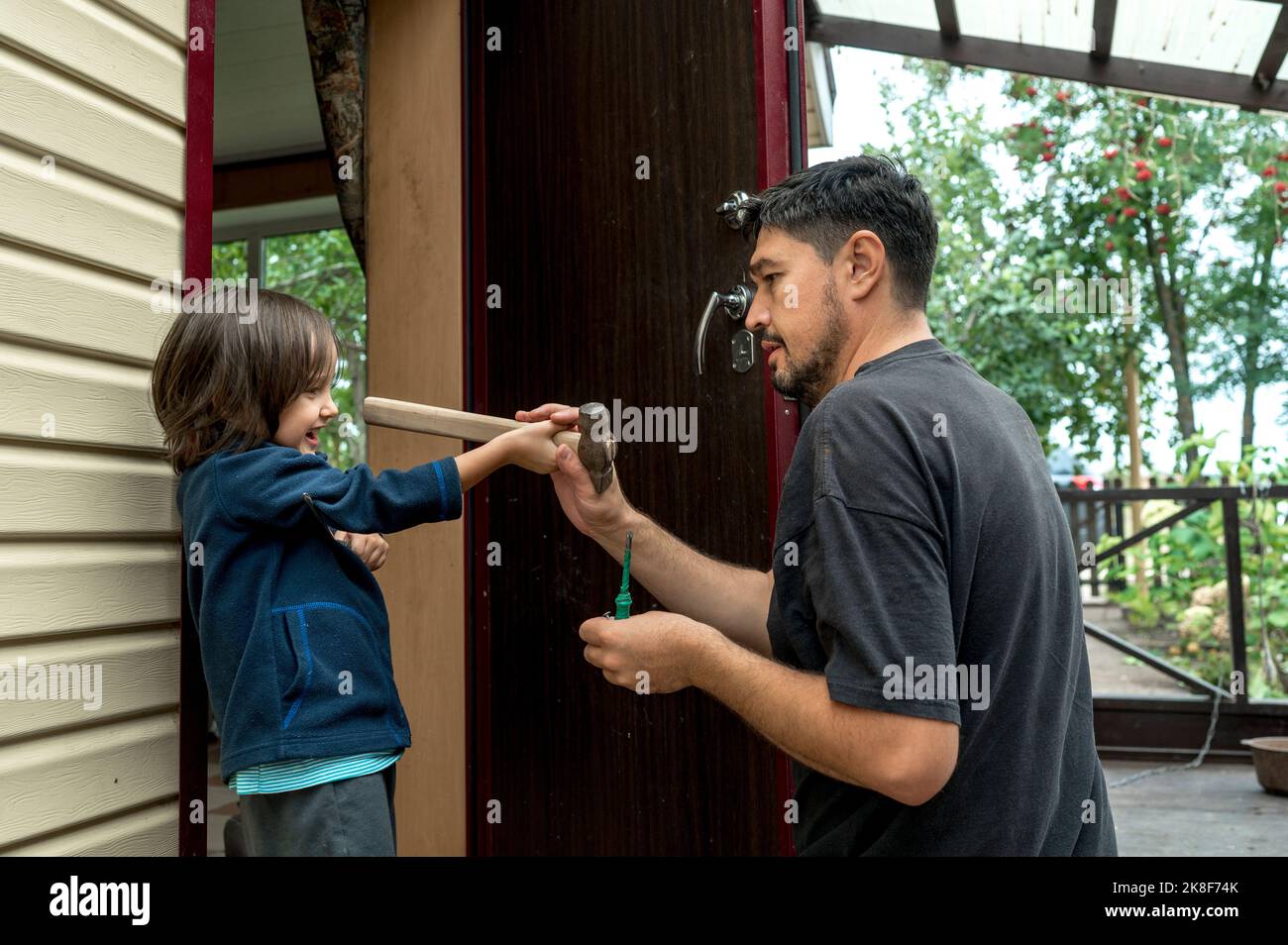 Smiling boy giving hammer to father at doorway Stock Photo - Alamy