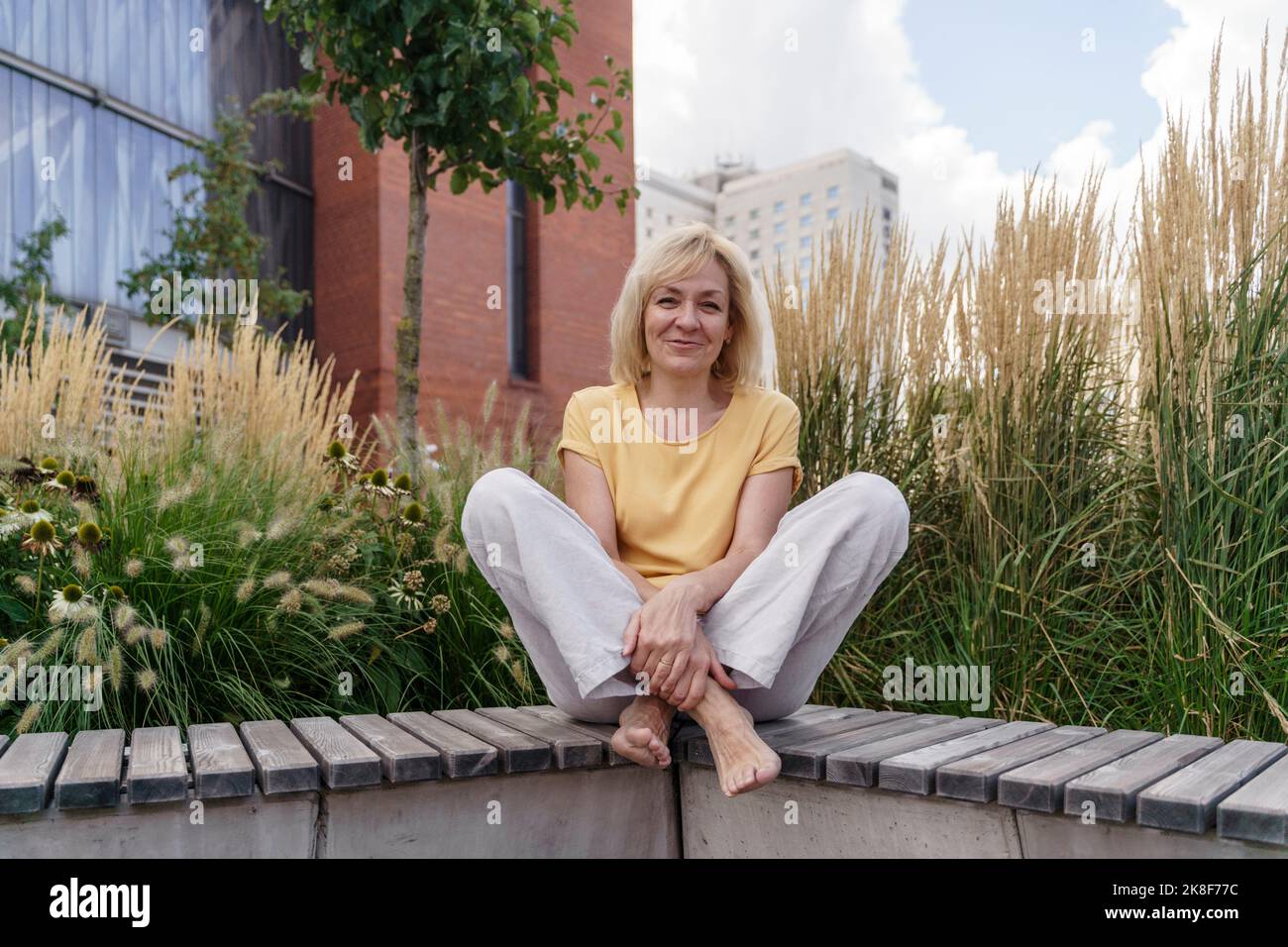 Happy woman with barefoot sitting on bench Stock Photo - Alamy