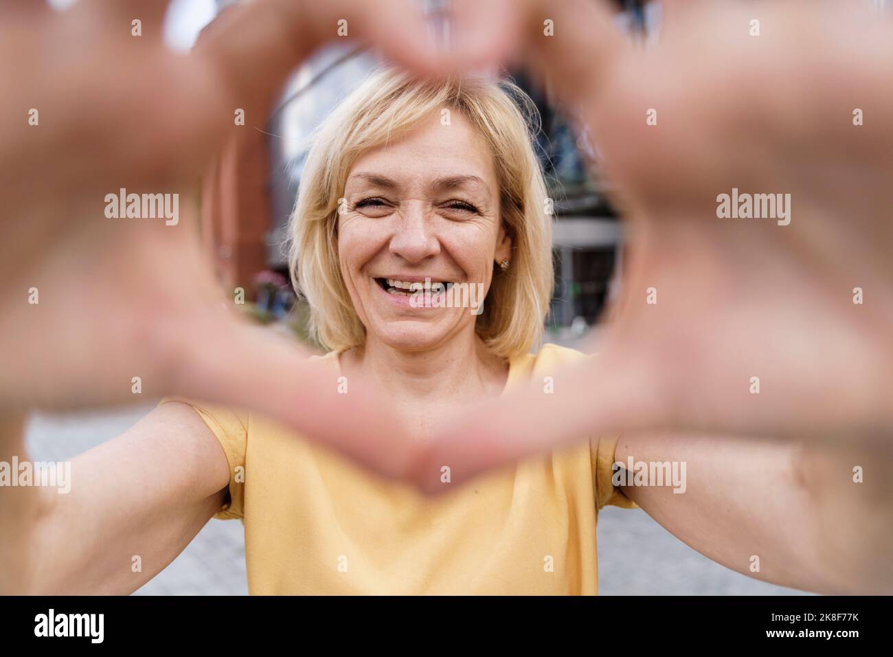 Happy woman making heart shape with hands Stock Photo - Alamy
