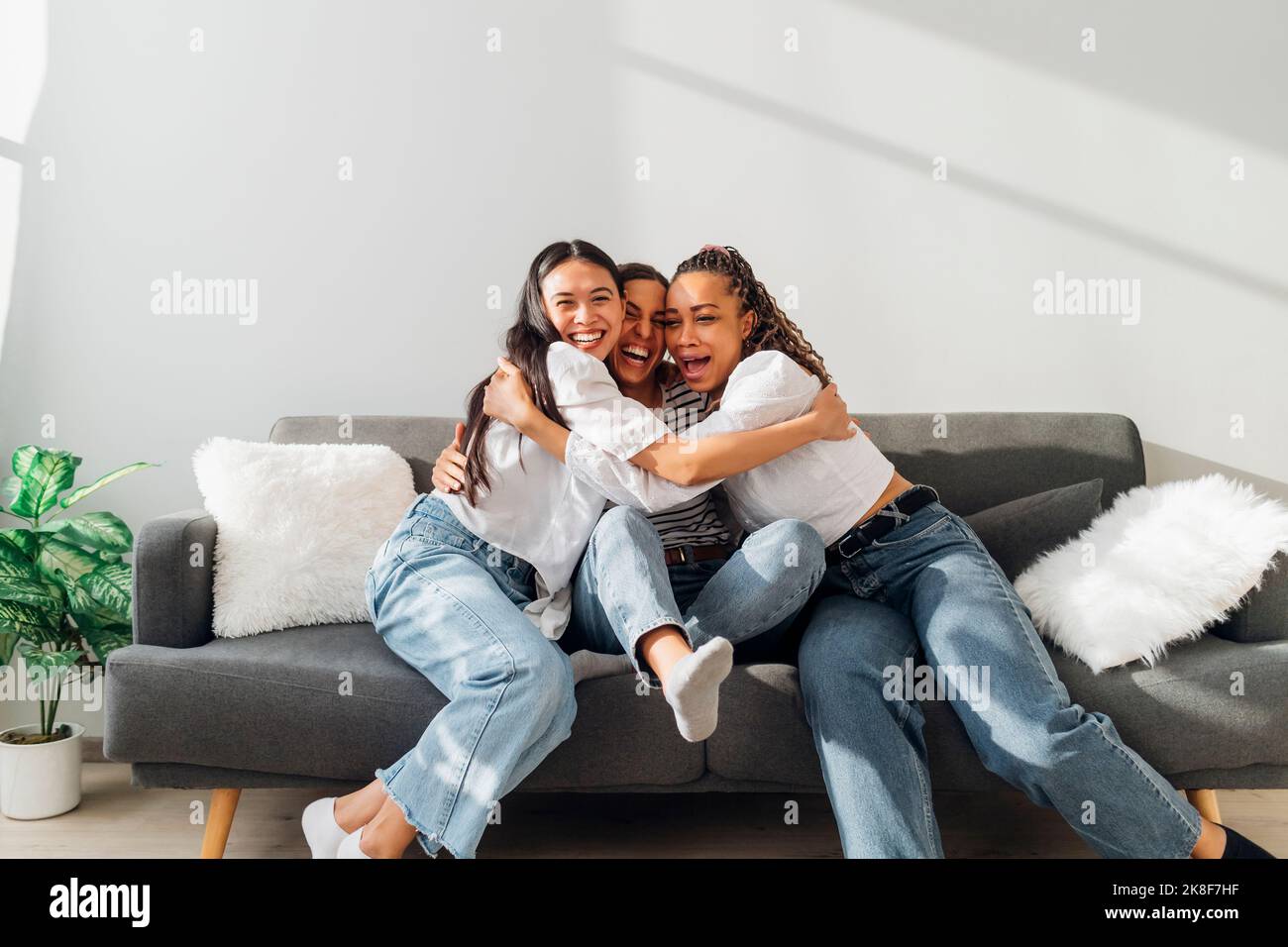 Laughing embracing friends on couch hi-res stock photography and images ...