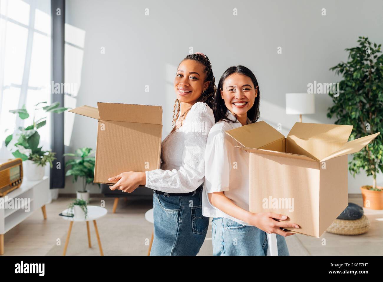 Happy friends with cardboard boxes moving in new house Stock Photo - Alamy