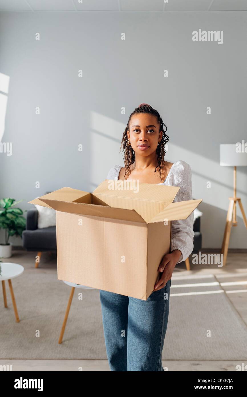 Woman carrying cardboard box standing in new house Stock Photo - Alamy