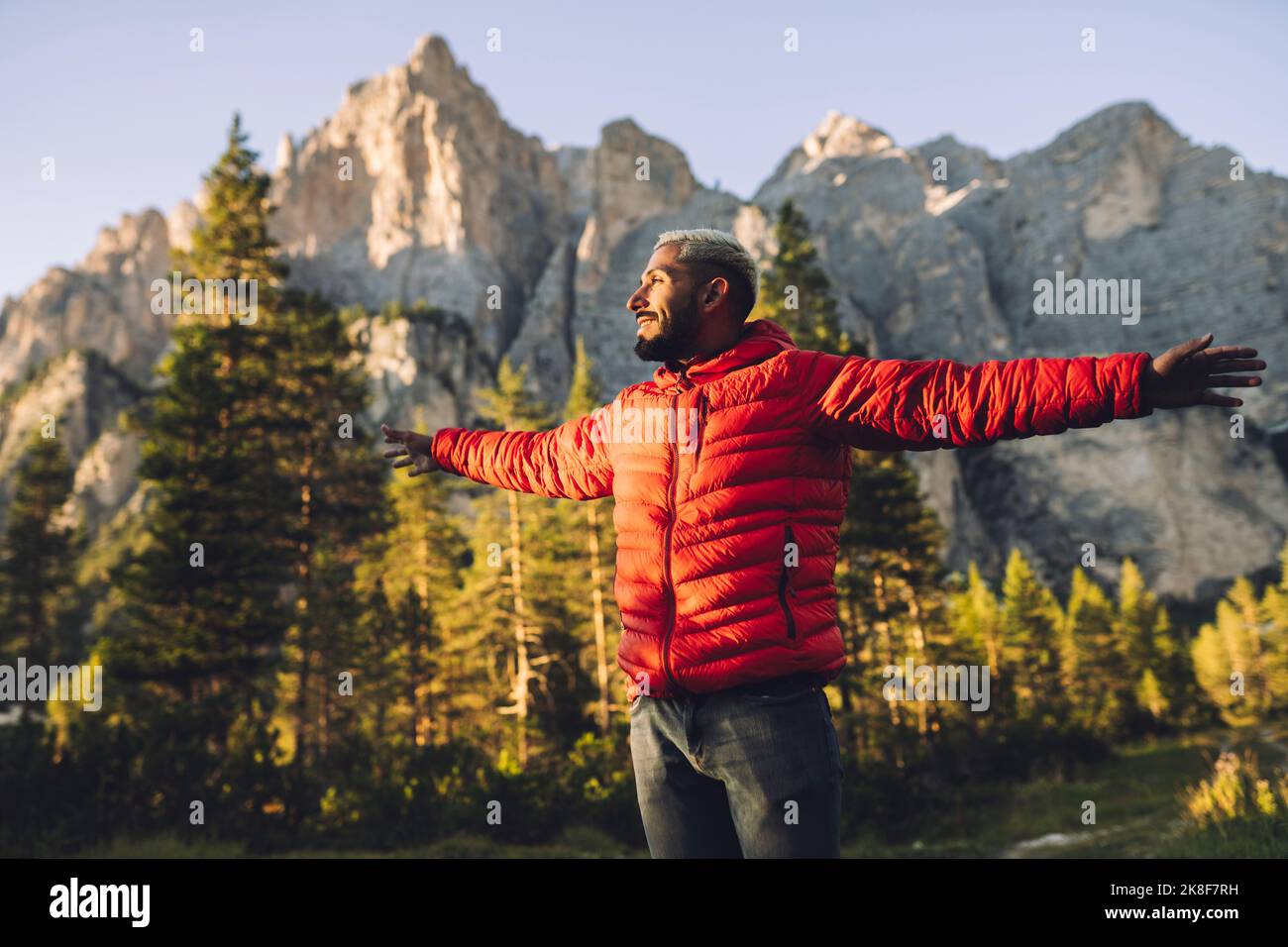 Smiling man with arms outstretched standing in front of Dolomites ...