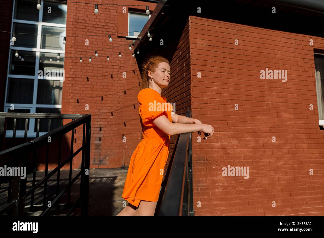 Thoughtful woman leaning on railing Stock Photo - Alamy