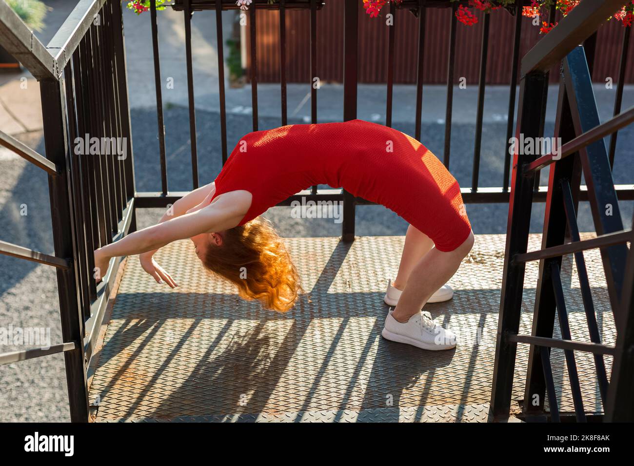 Woman wearing red dress bending over backwards on balcony Stock Photo ...