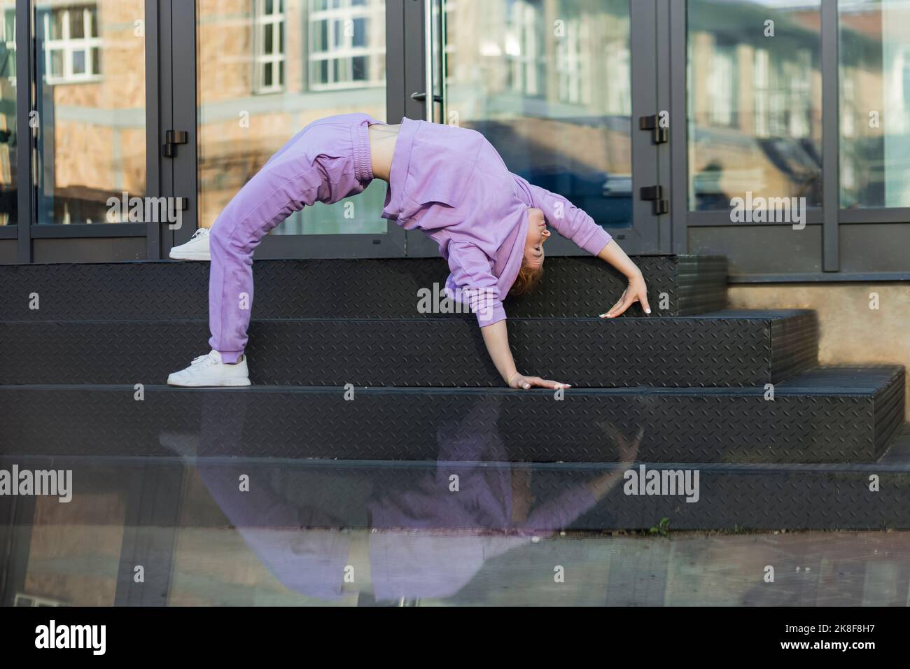 Woman exercising bridge position on staircase in front of glass door ...