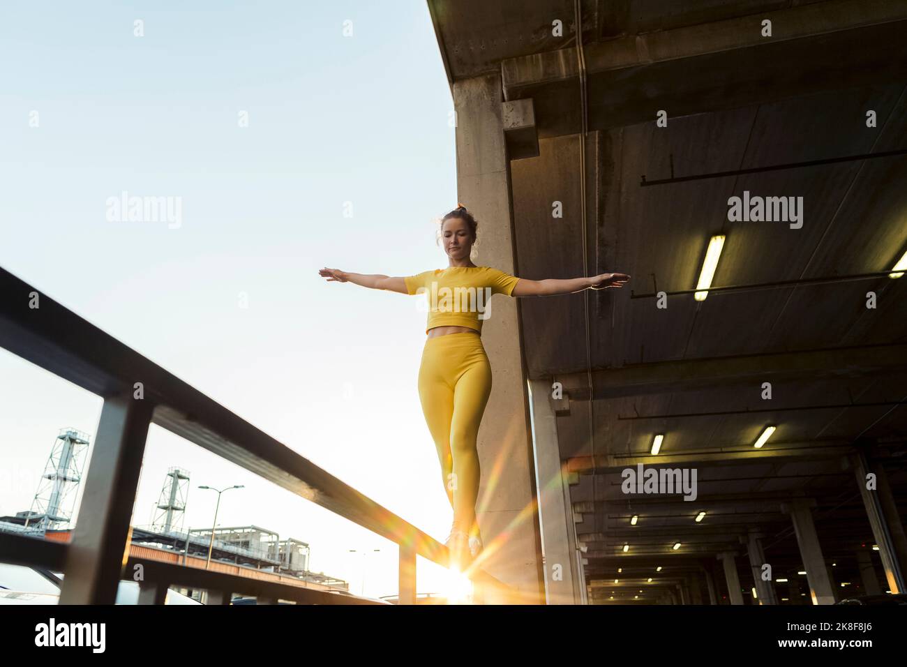 Woman with arms outstretched walking on back lit railing Stock Photo ...