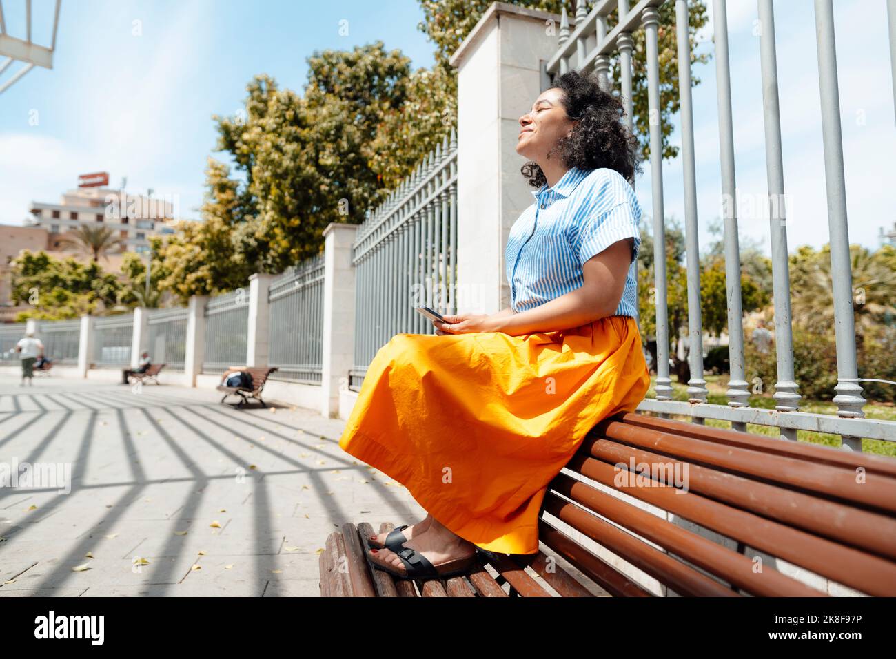 Woman sitting on bench enjoying the sunshine hi-res stock photography ...