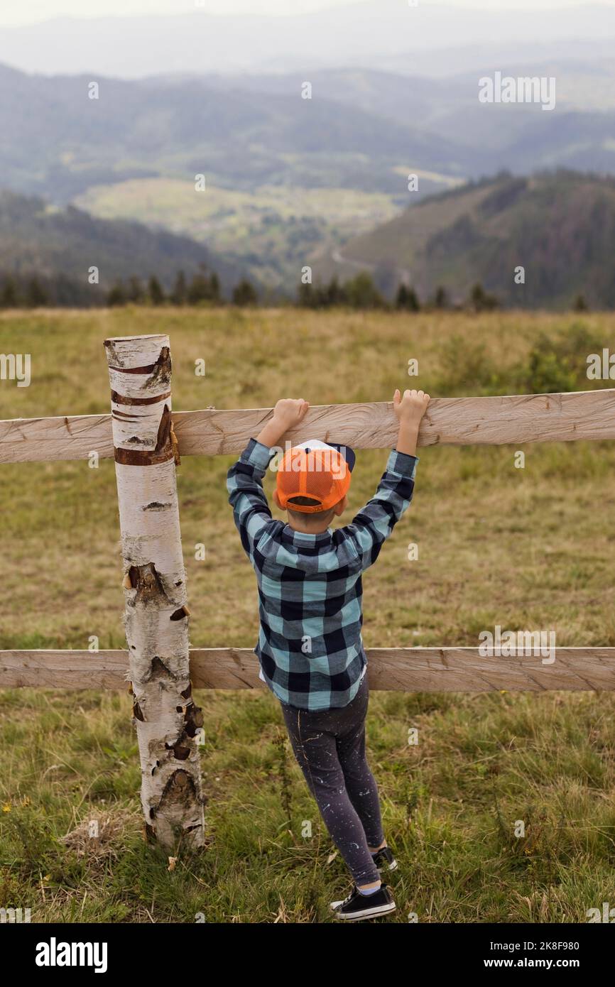 Boy wearing cap playing by fence at farm Stock Photo - Alamy