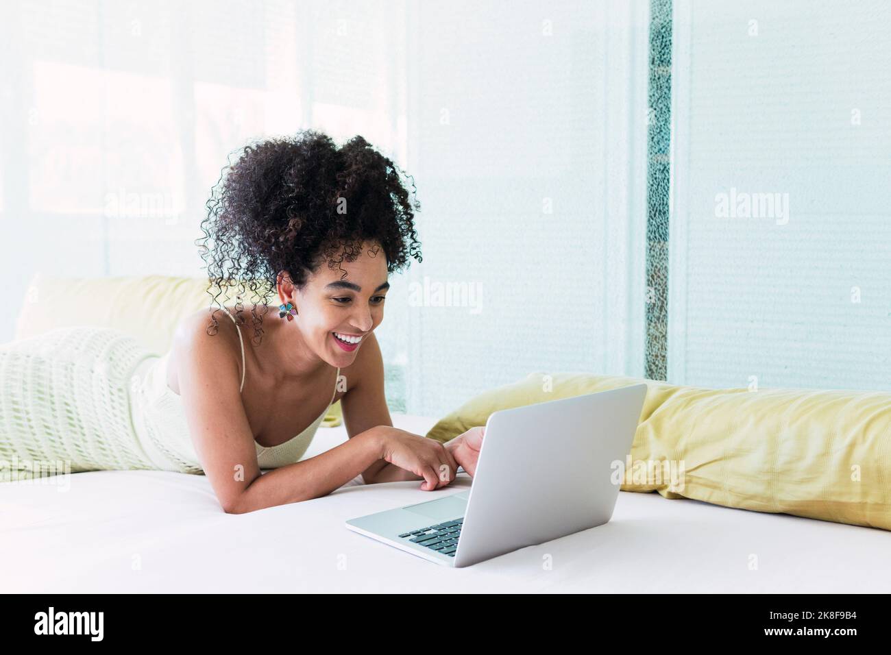 Happy woman lying on bed and using laptop at home Stock Photo - Alamy
