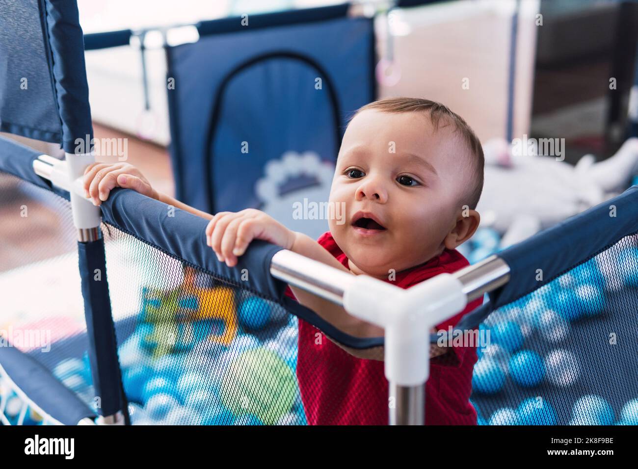 Cute baby boy standing in playpen at home Stock Photo - Alamy