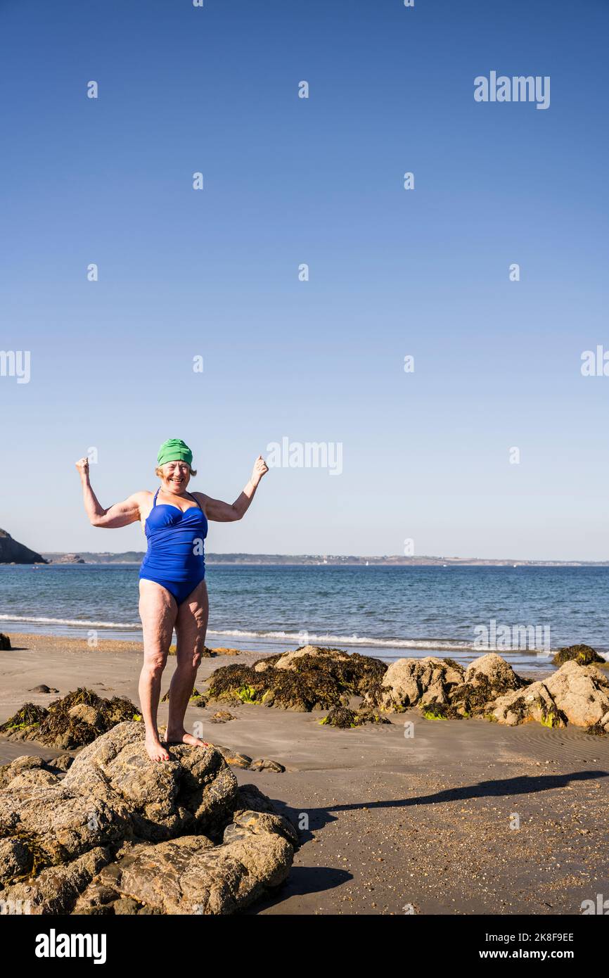 Woman standing on rock flexing muscles at beach Stock Photo - Alamy