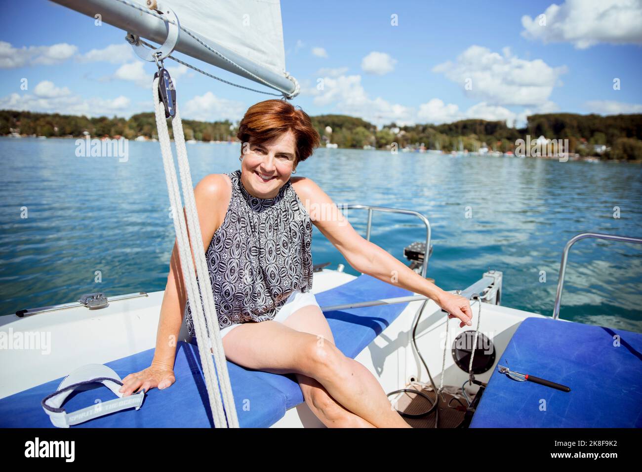 Smiling senior woman sitting with legs crossed on sailboat Stock Photo ...