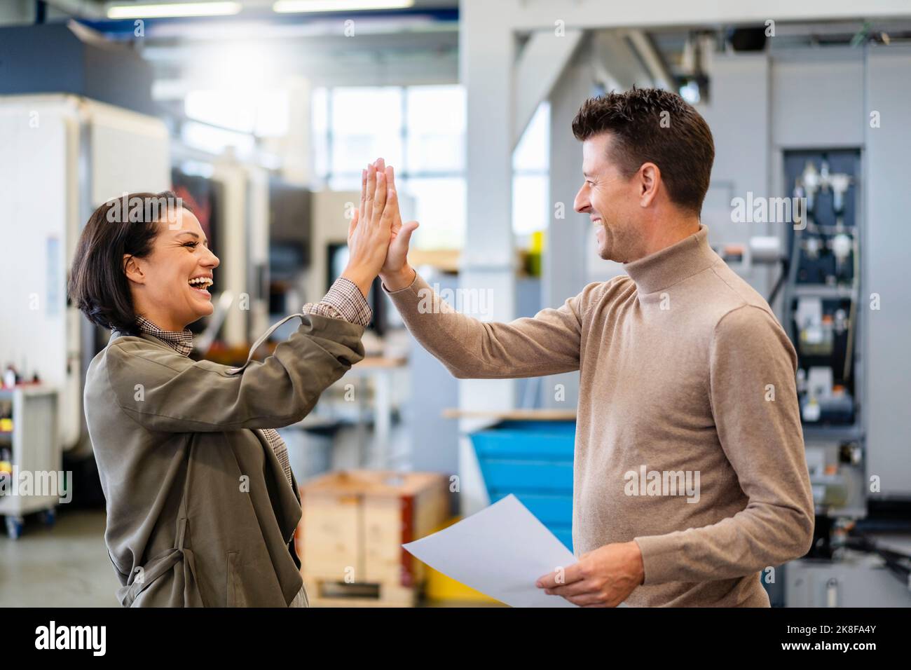 Happy businessman giving high five to businessman holding document in ...