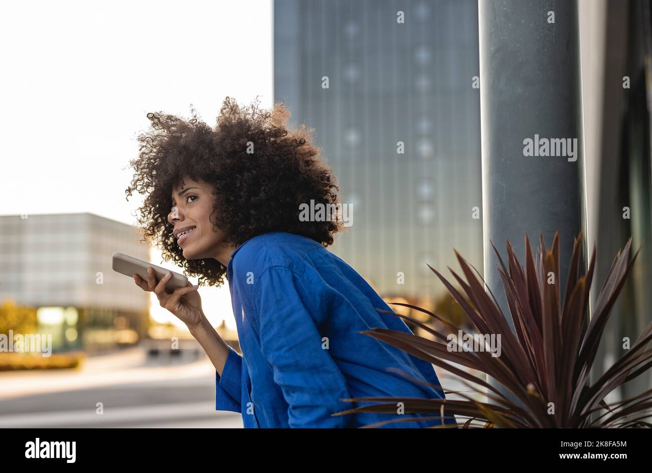 Woman with Afro hairstyle talking through speaker on mobile phone Stock ...