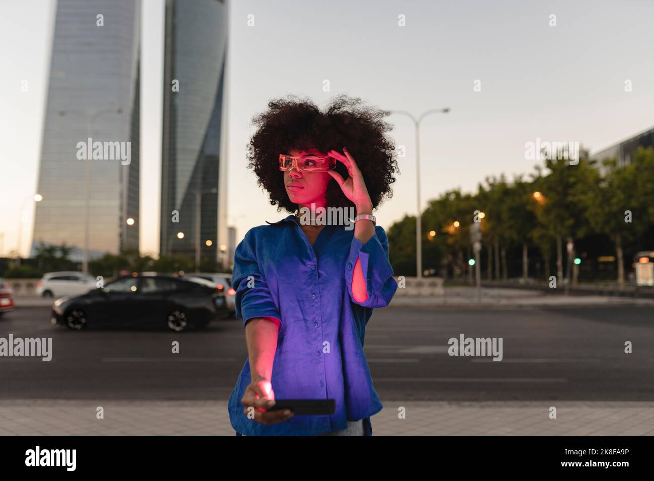Red light falling on Afro woman face wearing smart glasses holding ...
