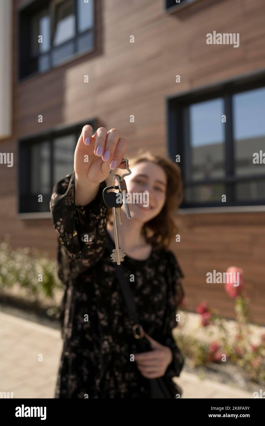 Young woman showing house keys standing in front of building Stock ...