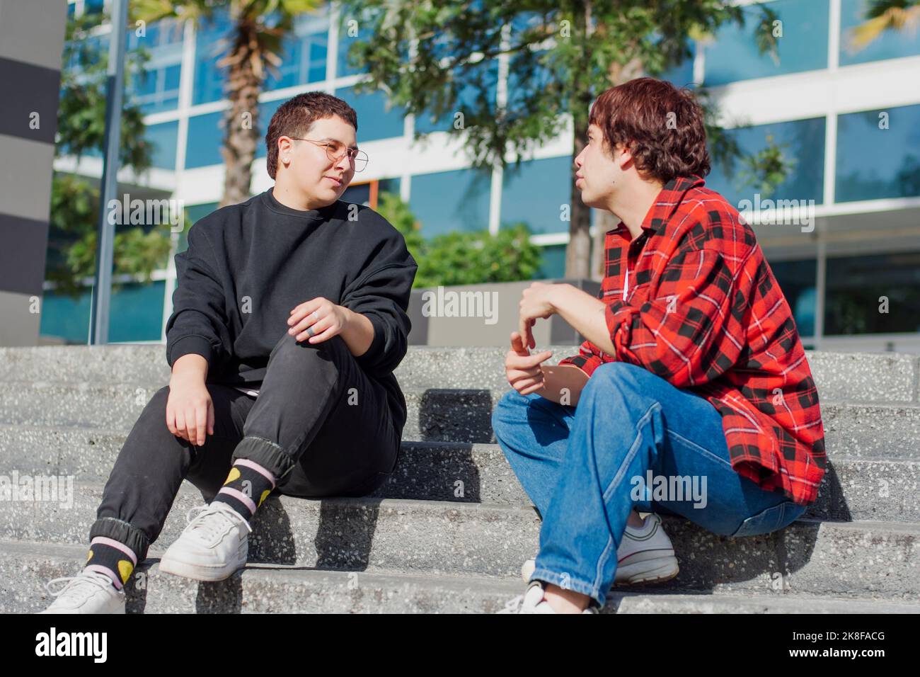 Non-binary couple sitting together on staircase in front of building ...