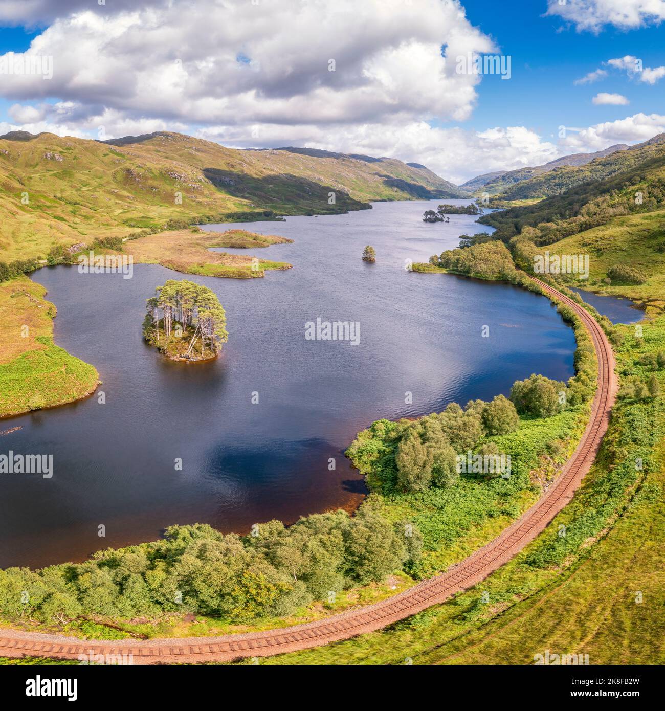 Scenic view of West Highland railroad track by lake,Loch Eilt, Scotland ...