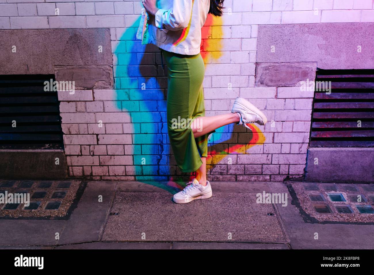 Woman standing on one leg in front of brick wall Stock Photo - Alamy