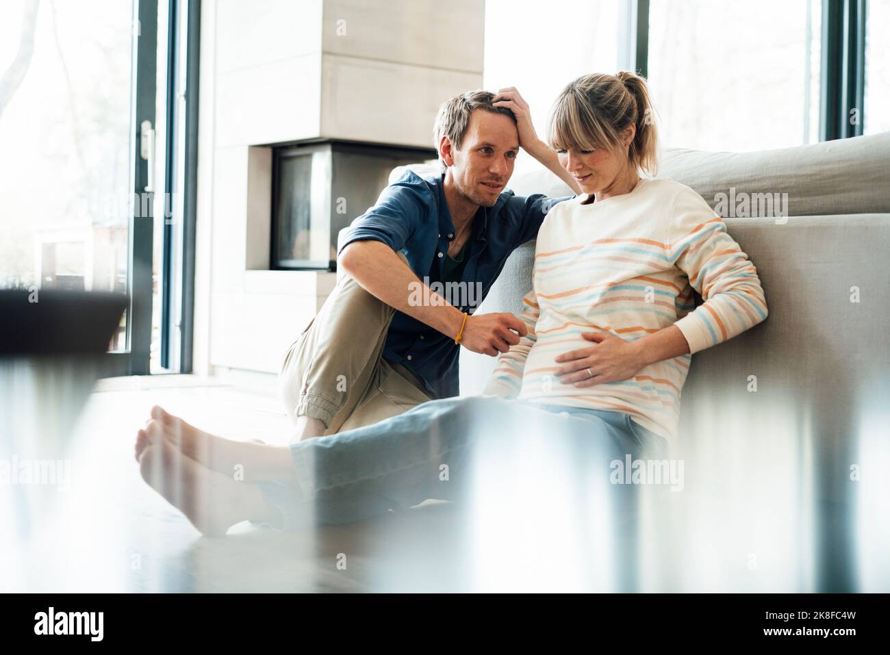 Man talking with pregnant woman touching belly sitting at home Stock ...