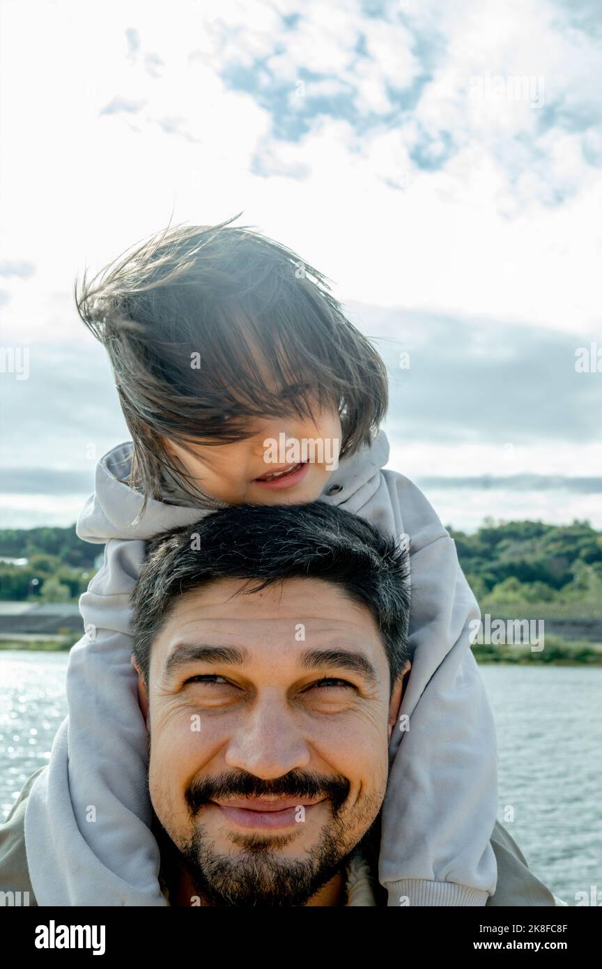 Smiling father carrying son on shoulder in front of river Stock Photo ...